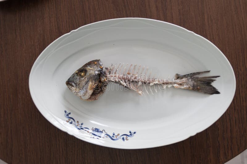 Fish Bone Left Overs with a Sliced Lemon on a White Oval Plate. Stock ...