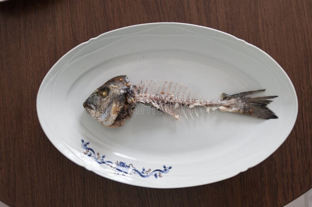 Fish Bone Left Overs with a Sliced Lemon on a White Oval Plate. Stock ...