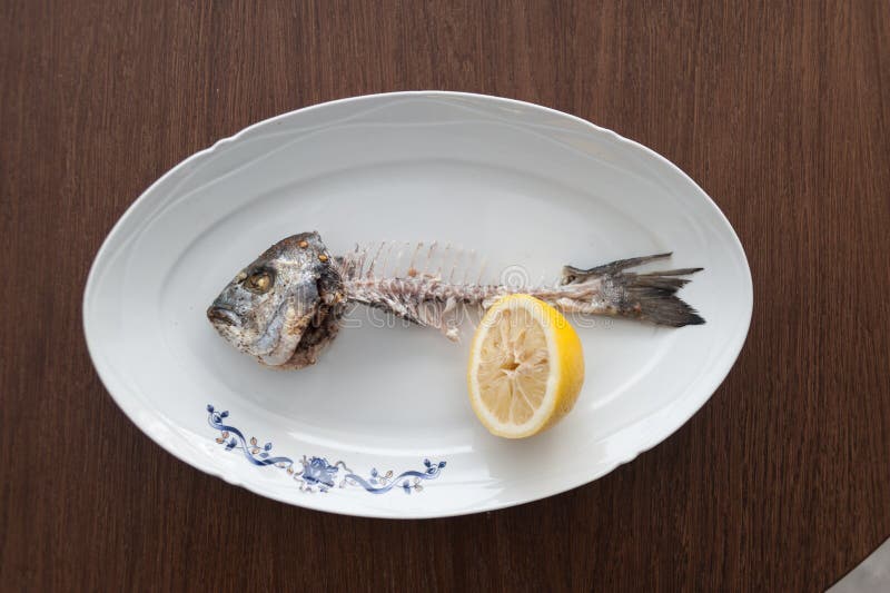 Fish Bone Left Overs with a Sliced Lemon on a White Oval Plate. Stock ...