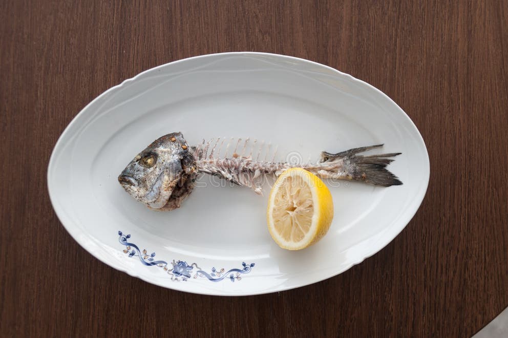 Fish Bone Left Overs with a Sliced Lemon on a White Oval Plate. Stock ...