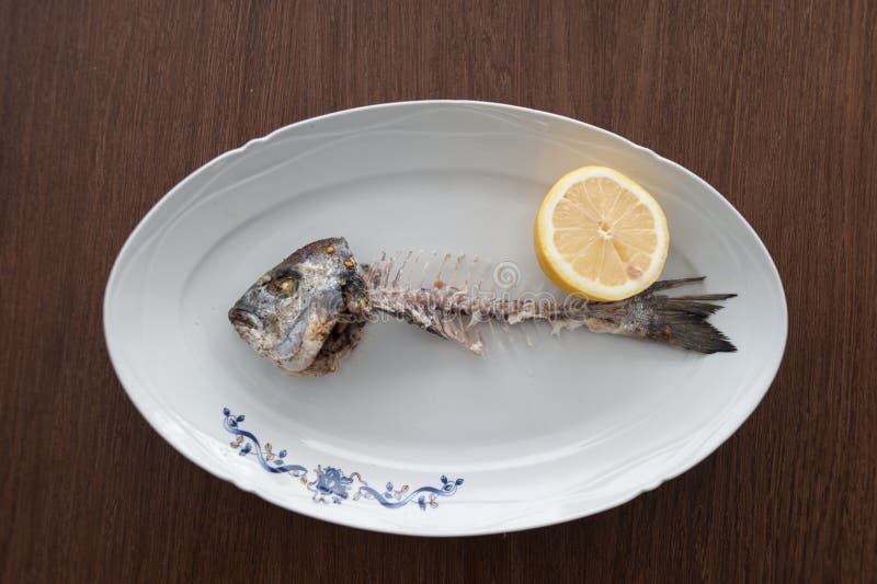 Fish Bone Left Overs with a Sliced Lemon on a White Oval Plate. Stock ...