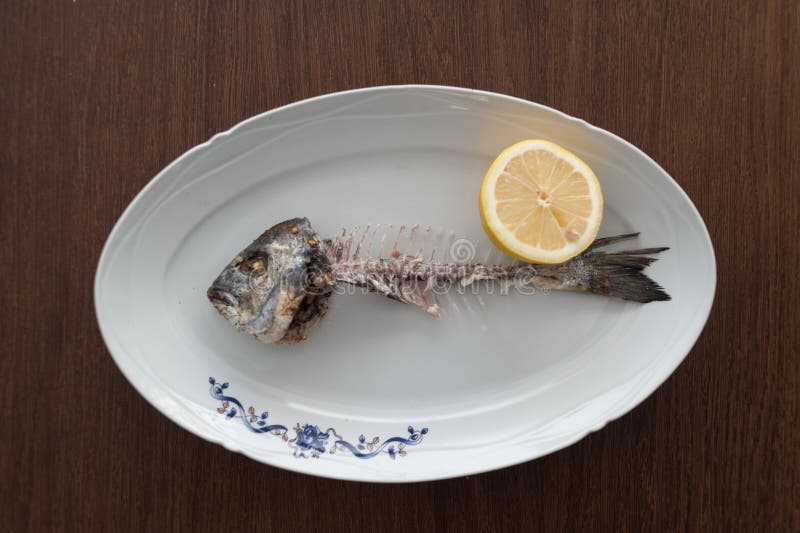 Fish Bone Left Overs with a Sliced Lemon on a White Oval Plate. Stock ...