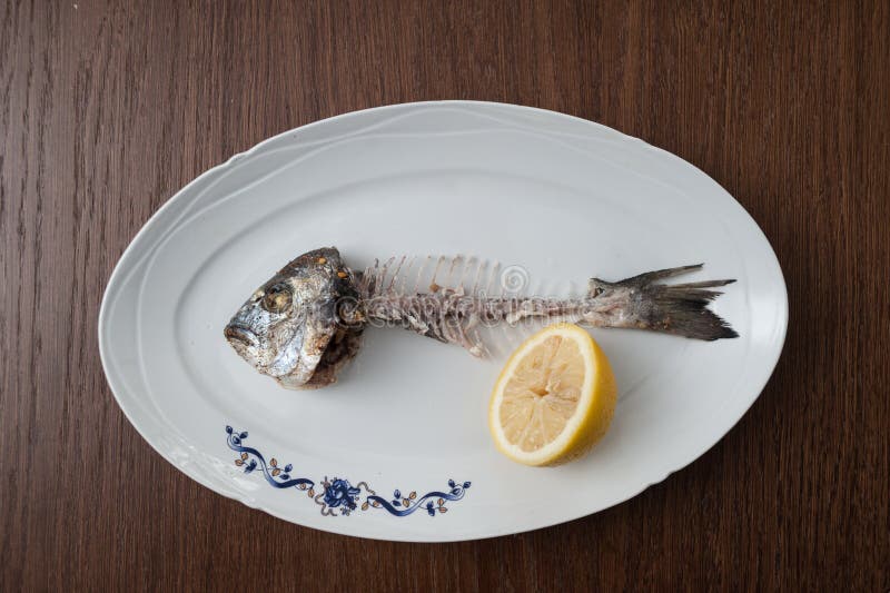 Fish Bone Left Overs with a Sliced Lemon on a White Oval Plate. Stock ...