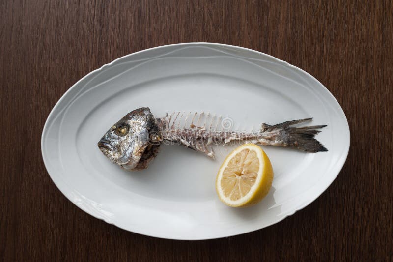 Fish Bone Left Overs with a Sliced Lemon on a White Oval Plate. Stock ...