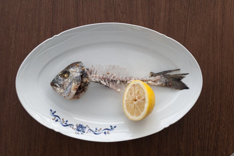 Fish Bone Left Overs with a Sliced Lemon on a White Oval Plate. Stock ...