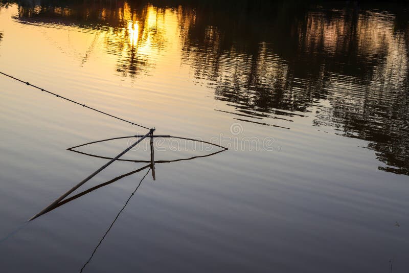 Fish Net Fishing Deep in the Water with Sunset Reflecting on Water ...