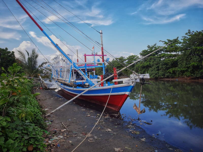 A Fishing Boat that is Leaning on the Edge of a River Whose Water is ...