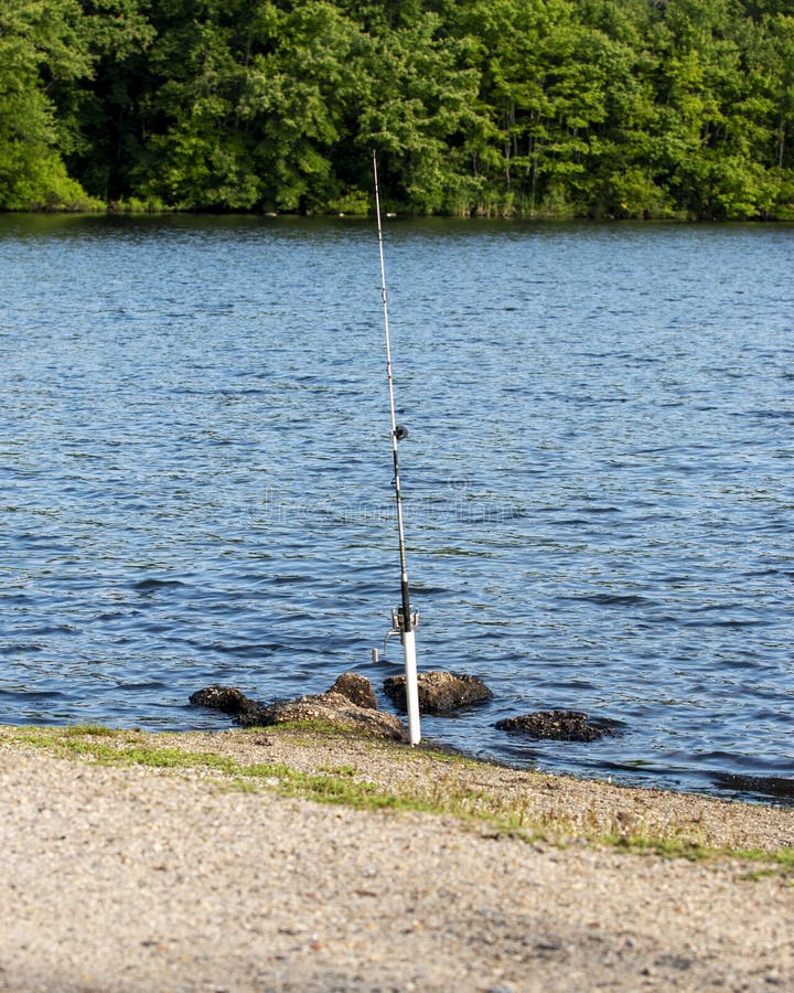 A Fishing Pole Sitting on the Shore of a Lake Stock Photo - Image of ...