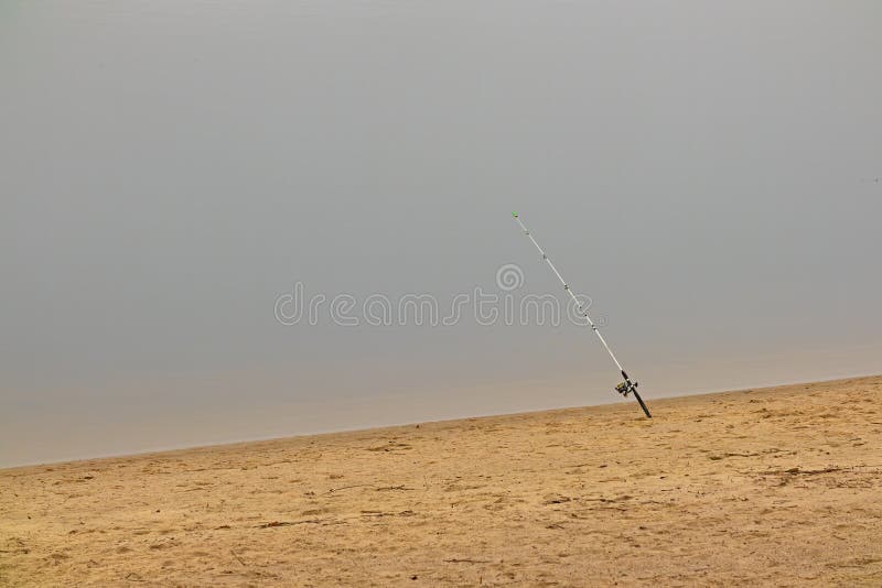 Fishing Rod on a Sandy Shore on a Cloudy Day. Calm Water without Waves ...