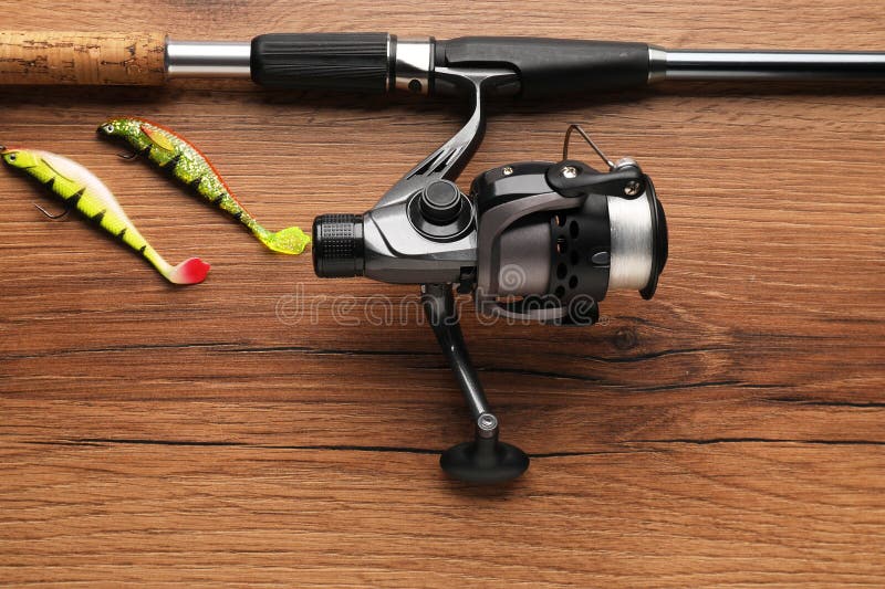 A Spinning Rod with a Reel and Fishing Baits Lies on a Wooden Table ...