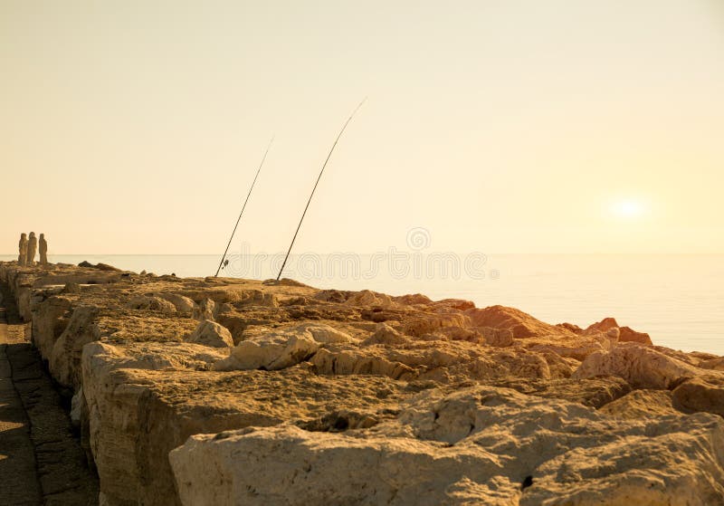 Fishing rods at sunset stock photo. Image of rock, sunset - 76838000