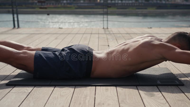 A Fit Caucasian Man Does Superman Back Extensions on a Black Mat ...
