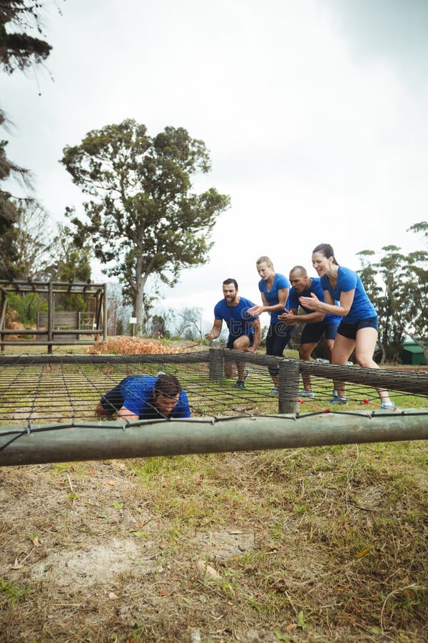 Fit Man Crawling Under the Net during Obstacle Course while Fit People ...