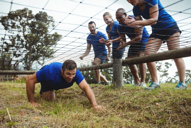 Fit Man Crawling Under the Net during Obstacle Course while Fit People ...