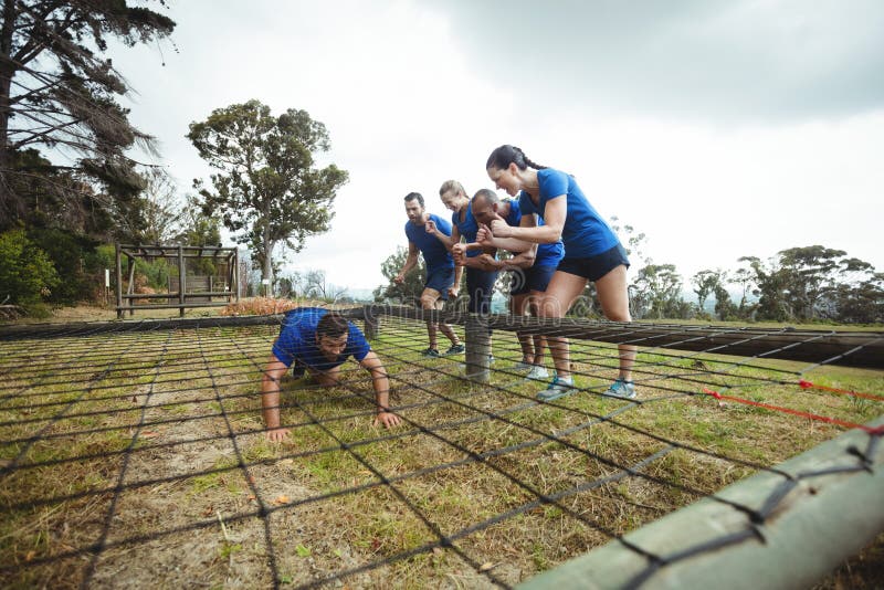 Fit Man Crawling Under the Net during Obstacle Course while Fit People ...