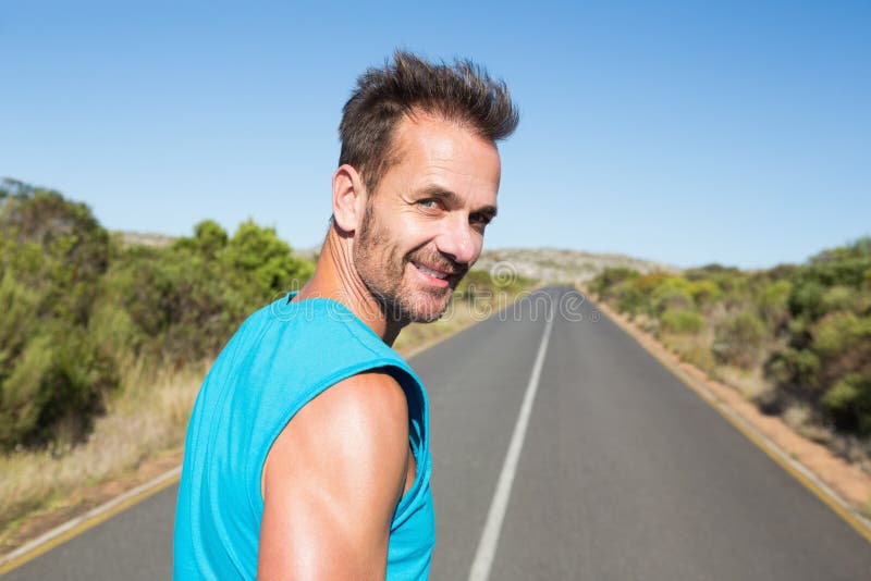Fit Man Jogging on the Open Road Smiling at Camera Stock Photo - Image ...