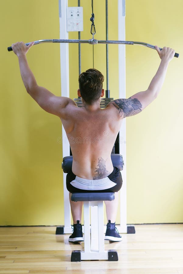 Fit Man on Lat Pull Down Machine at the Health Club. Work Out on Pull ...