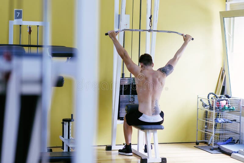 Fit Man on Lat Pull Down Machine at the Health Club. Work Out on Pull ...