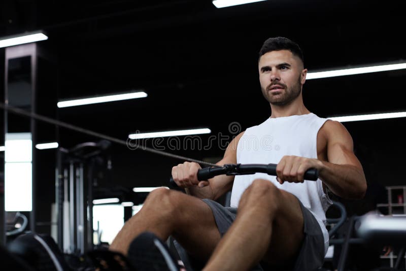 Fit and Muscular Man Using Rowing Machine at Gym Stock Image - Image of ...