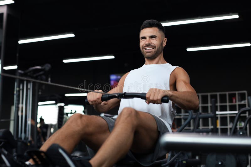 Fit and Muscular Man Using Rowing Machine at Gym. Stock Image - Image ...