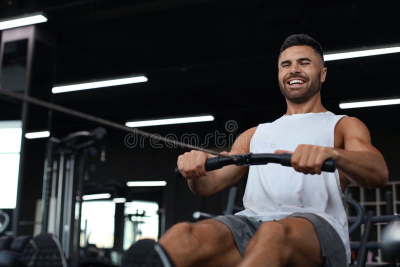 Fit and Muscular Man Using Rowing Machine at Gym. Stock Image - Image ...