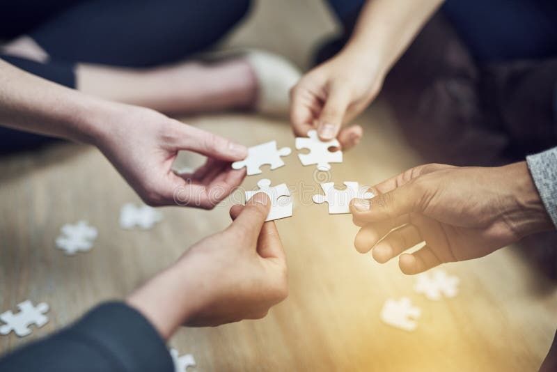 We Fit Together. Shot of a Group of People Building a Puzzle Together ...