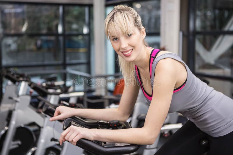 Fit woman on exercise bike stock photo. Image of female - 66972376