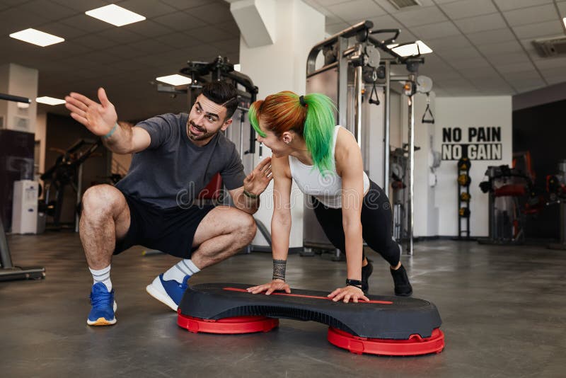 Fit Woman Doing Raised Push Up Exercise with Male Trainer Assistance ...