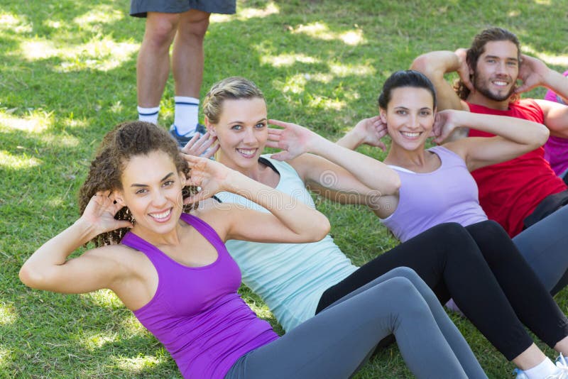 Fitness Group Doing Sit Ups in Park with Coach Stock Image - Image of ...