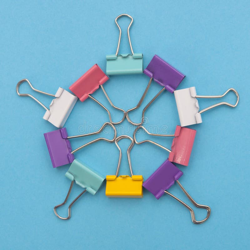Five Binder Clips of Different Colors on a Blue Paper Background Making ...