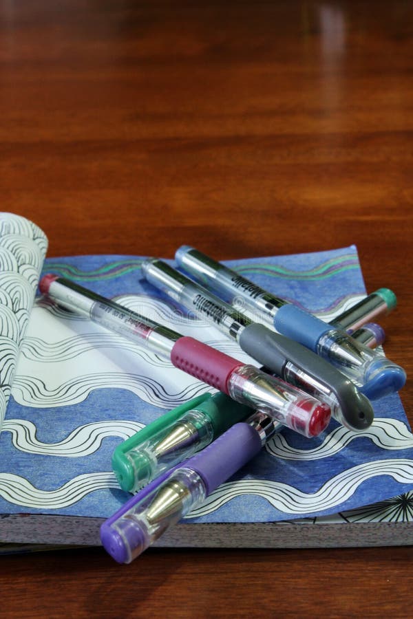 Five Different Colored Metallic Gel Pens Stacked on a Partially Colored ...
