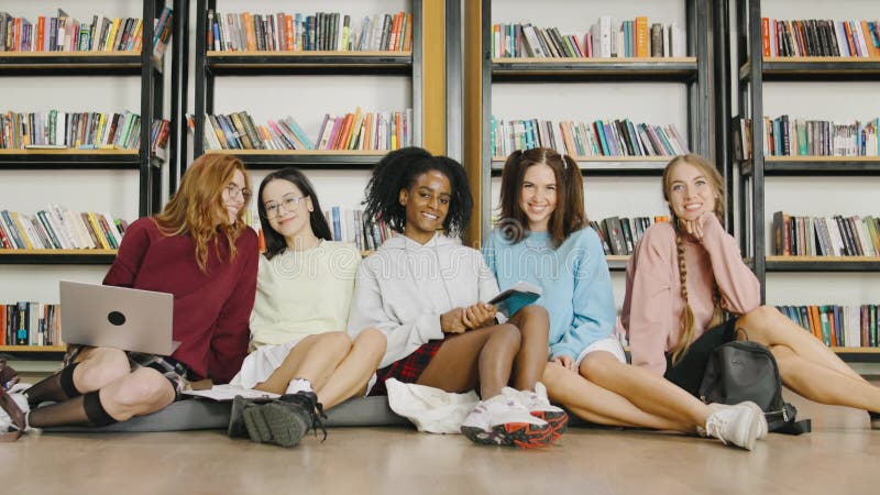 Five Happy Multiethnic Female Students Sit on the Floor in a University ...