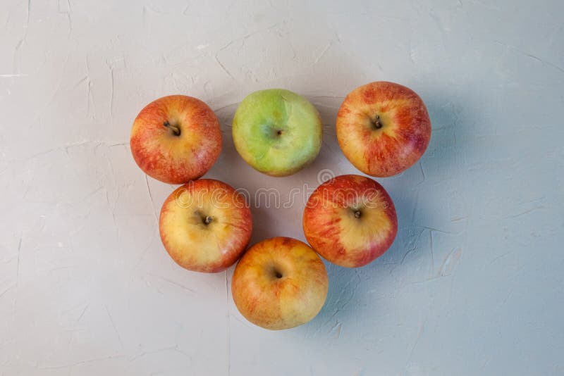 Five Red and One Green Apples Lie in the Shape of a Triangle on a Gray ...