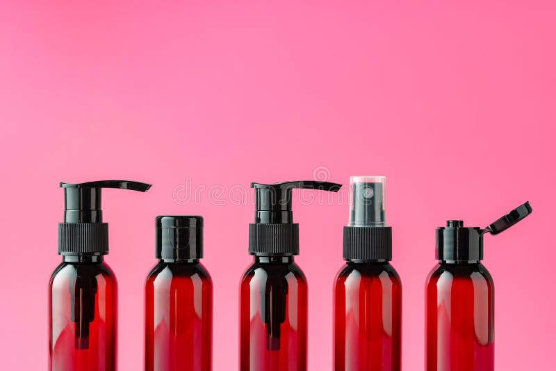 Five Red Plastic Bottles with Black Pumps and Sprays on a Pink ...