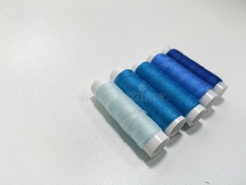 Row of Blue Sewing Thread Spools in Gradient Shades on White Background ...