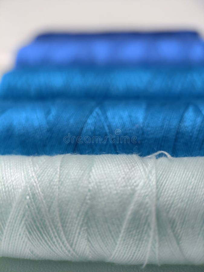 Row of Blue Sewing Thread Spools in Gradient Shades on White Background ...