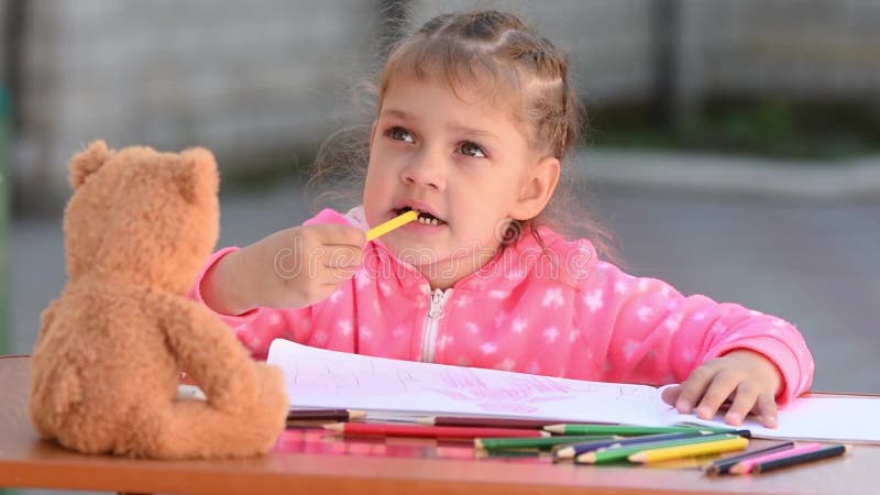 A 10-year-old Girl is Swinging on a Round Wicker Swing on a Playground ...