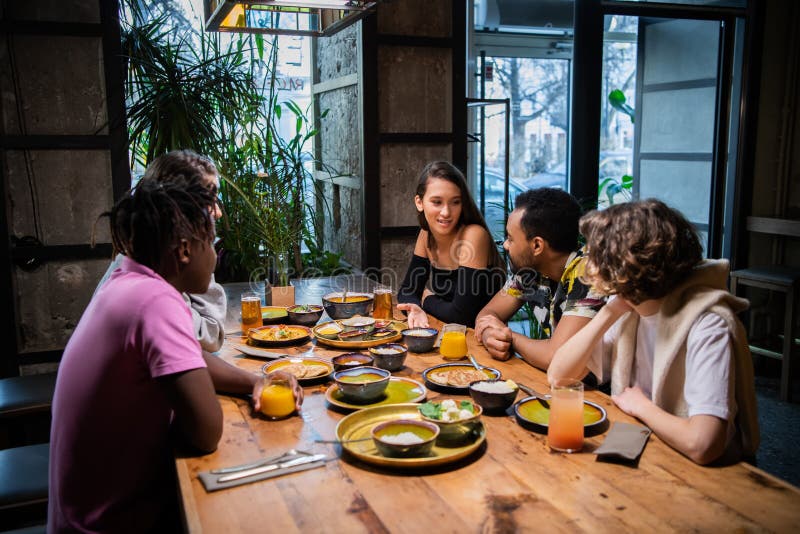 Five Young Friends Sitting at the Table in a Cafe, Chatting, Hav Stock ...
