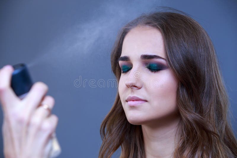Fixing makeup with a spray stock photo. Image of face - 176689064