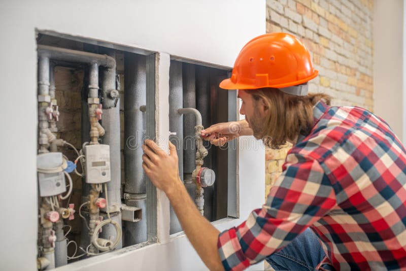 Construction Worker in Orange Helmet Fixing Something and Looking Busy ...
