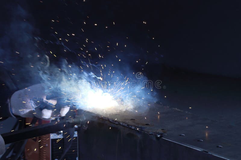 Flash from Electric Welding. Man in a Protective Mask from Light and ...
