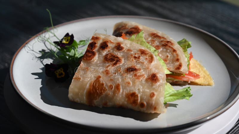 A Flatbread Stuffed with Fish and Cheese is Rotated on a Round Table ...