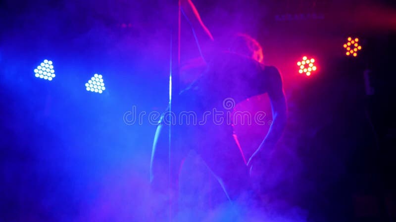 A Flexible Dancer Dances on a Pole Under the Light of Colorful ...