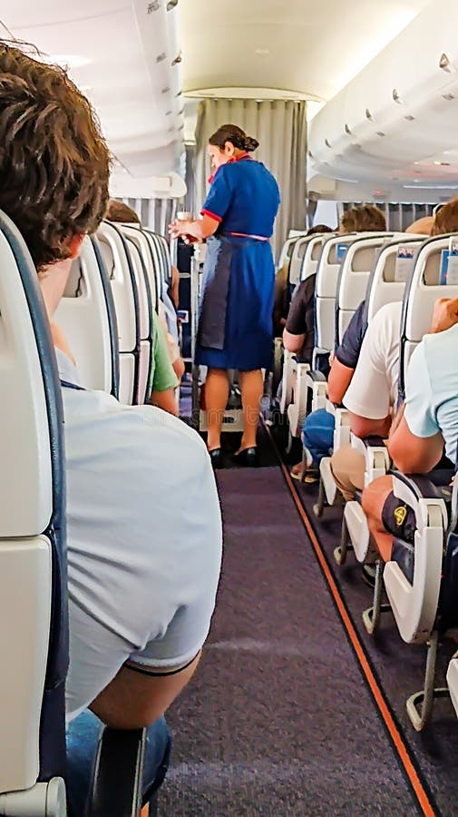 A Flight Attendant in the Aisle between Rows of Seats Editorial Stock ...