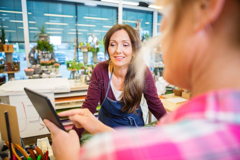 Florist Looking at Female Customer Using Digital Stock Image - Image of ...