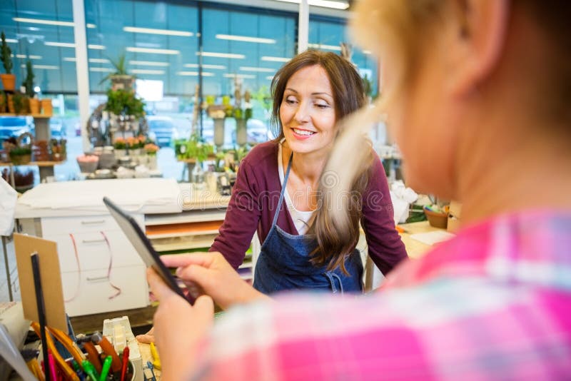 Florist Looking at Female Customer Using Digital Stock Photo - Image of ...