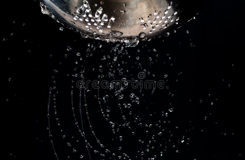Flow and Drops of Water through Holes in a Colander on a Dark ...