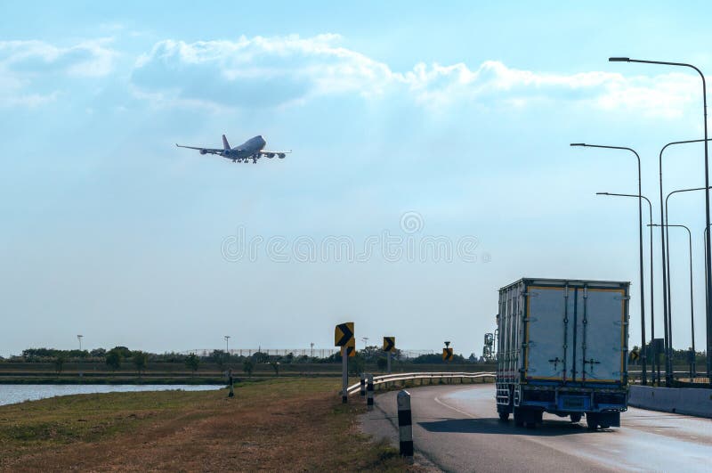 Flying Passenger Jet Plane on the Sky Over the Container Truck Running ...