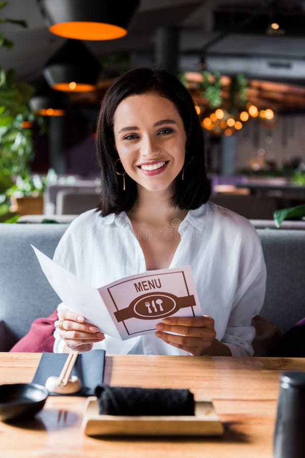 Focus of Cheerful Woman Sitting in Restaurant and Holding Menu Stock ...