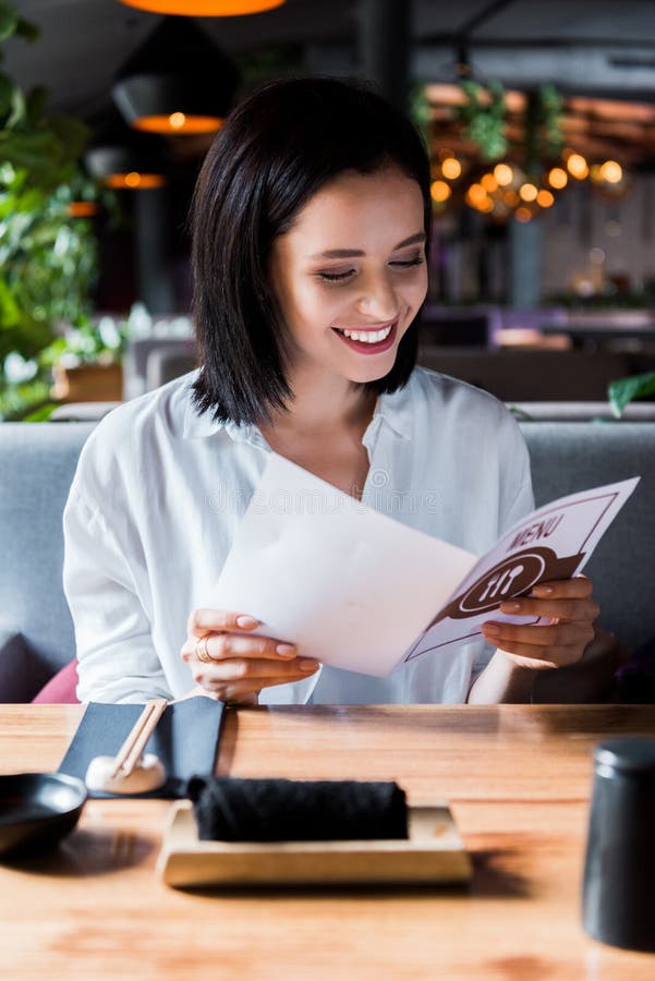 Focus of Cheerful Woman Sitting in Restaurant and Looking at Menu Stock ...